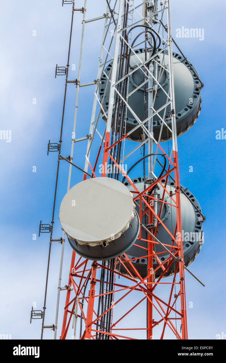 Telecommunication tower with cell phone antenna system against blue sky ...
