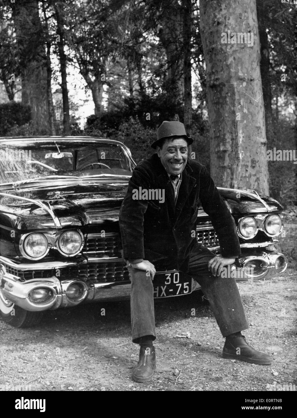 Actor Fernandel sits on hood of car Stock Photo - Alamy