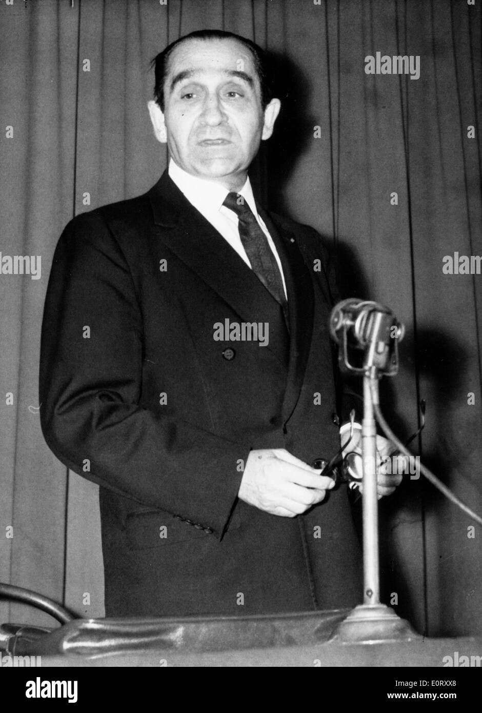 PIERRE MENDES-FRANCE stands at a microphone holding his glasses Stock ...