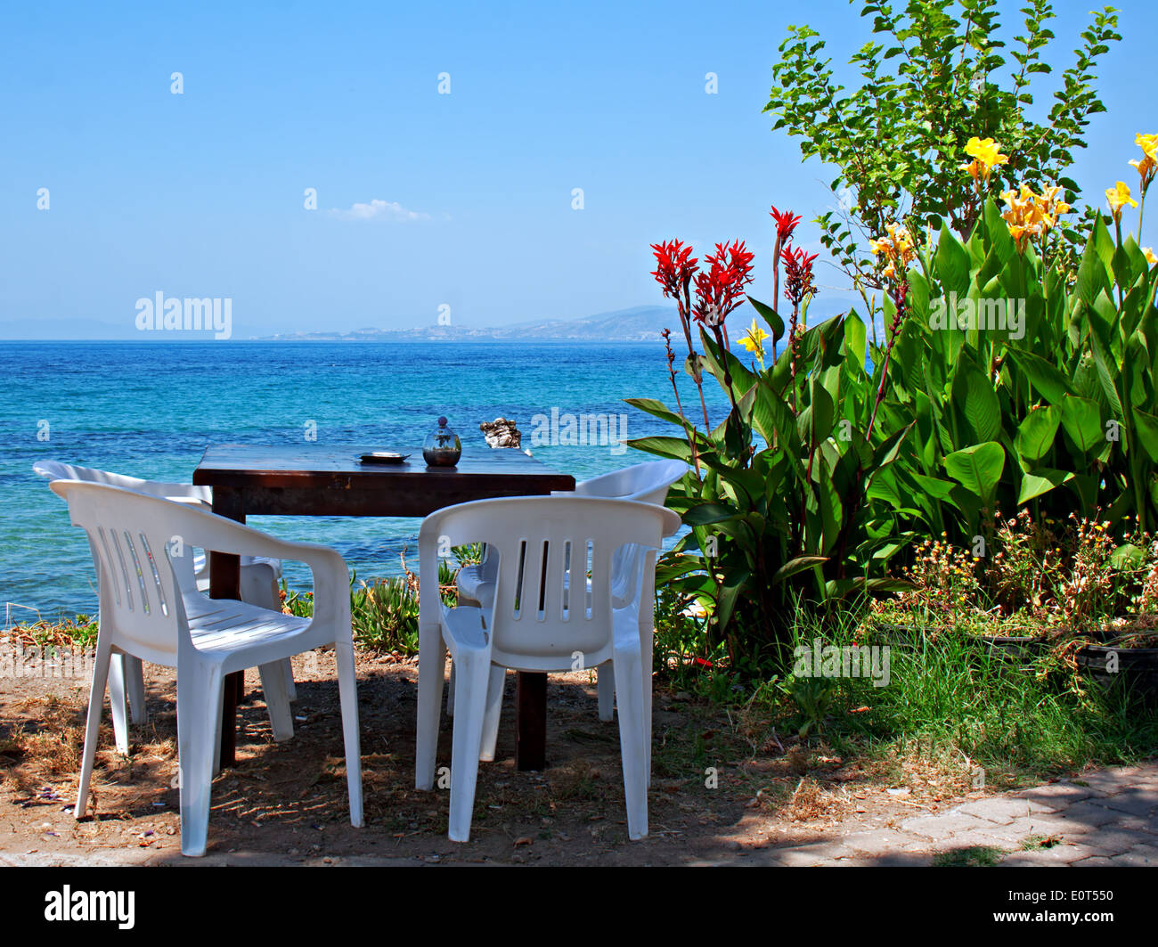 Table overlooking the sea, with colorful flowers Stock Photo - Alamy