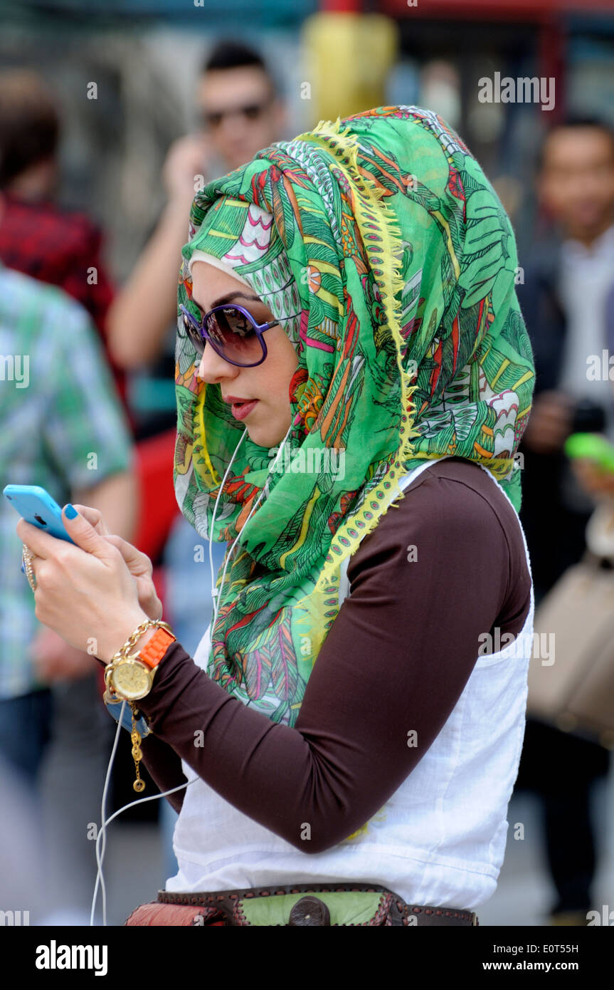 London, England, UK. Young Muslim woman in a colourful green headscarf ...