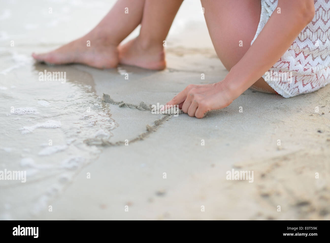Closeup on young woman drawing on sand Stock Photo - Alamy