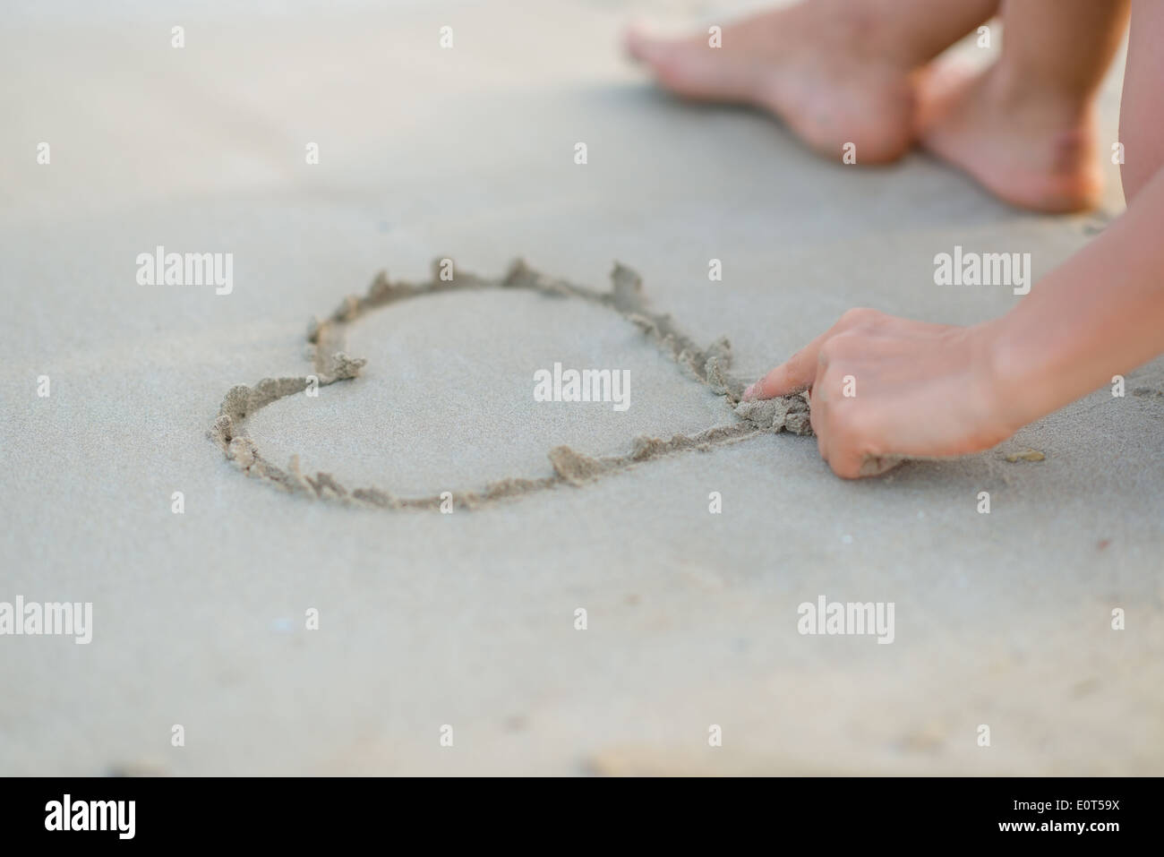 Closeup on young woman drawing on sand Stock Photo - Alamy