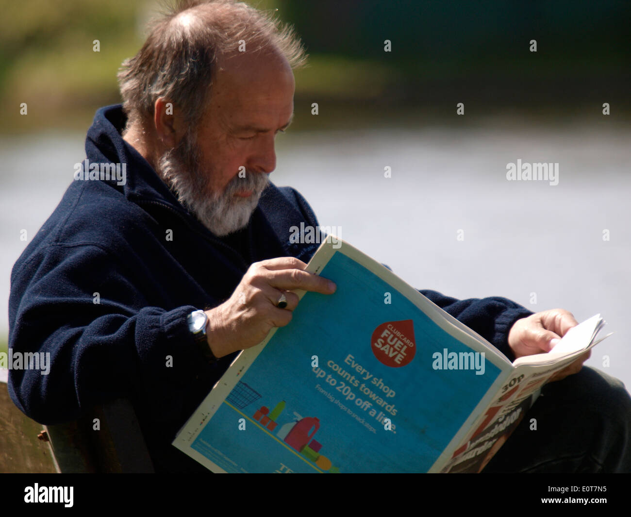 Older man sat on a public bench reading a newspaper, Cornwall, UK Stock ...