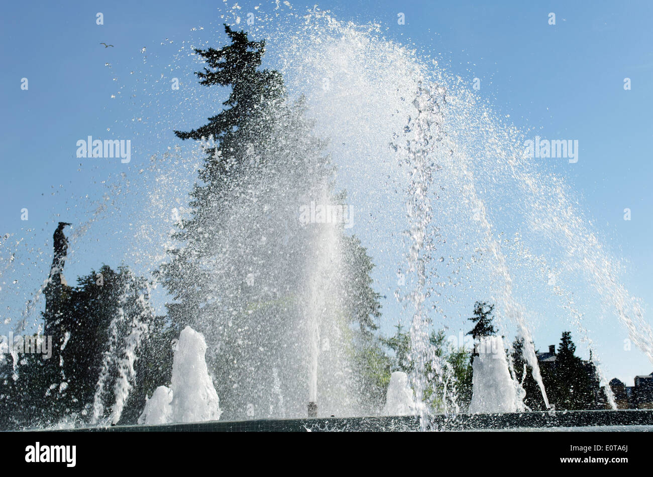 Water jet in a city park fountain with clear blue sky as background ...