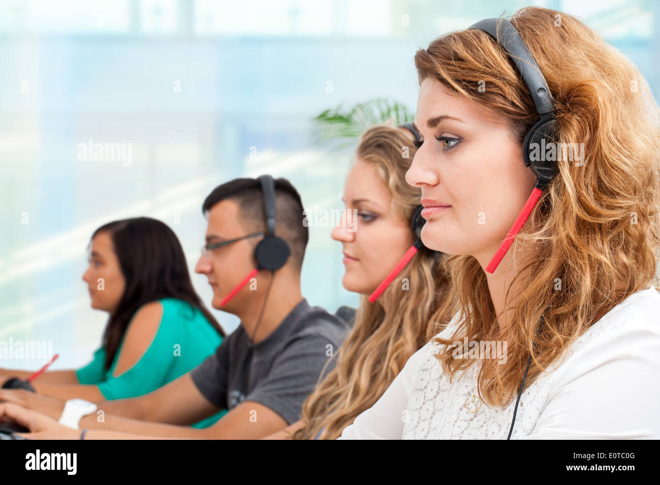 Young office workers with headsets giving customer service Stock Photo ...