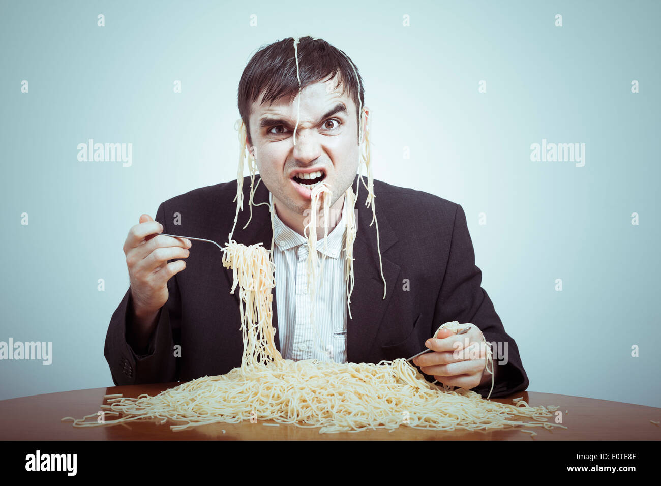 Greedy consumerism concept. Nasty businessman eating pasta on the table ...