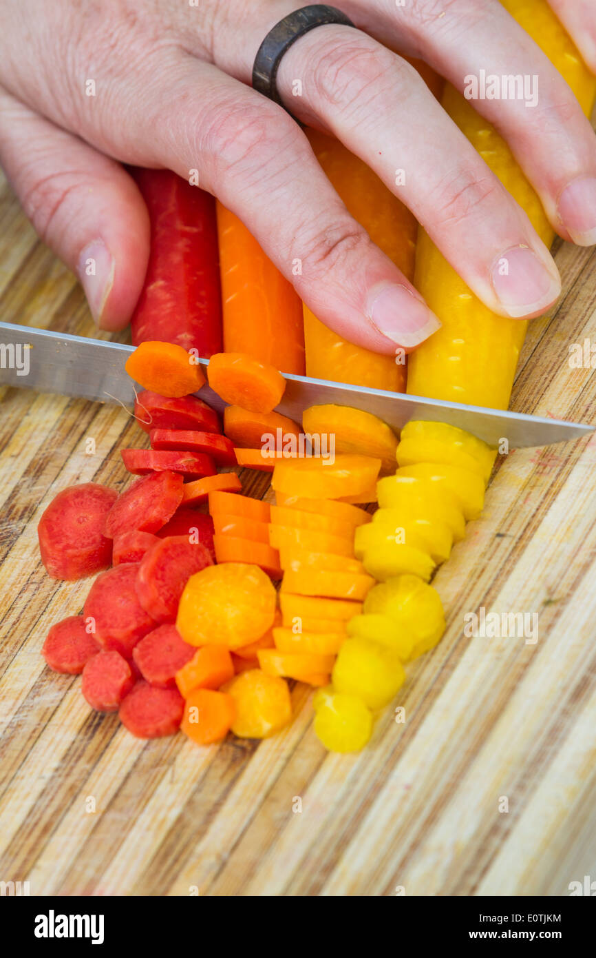 close-up in action of a cook slicing raw carrots arranged for a ...