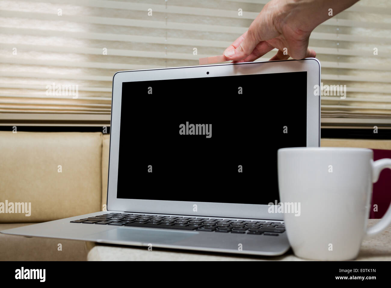 human hand putting a band aid on the webcam of the laptop in a home ...