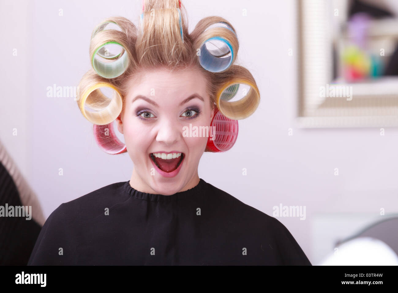 Portrait of funny happy woman in beauty salon. Cheerful blond girl with ...