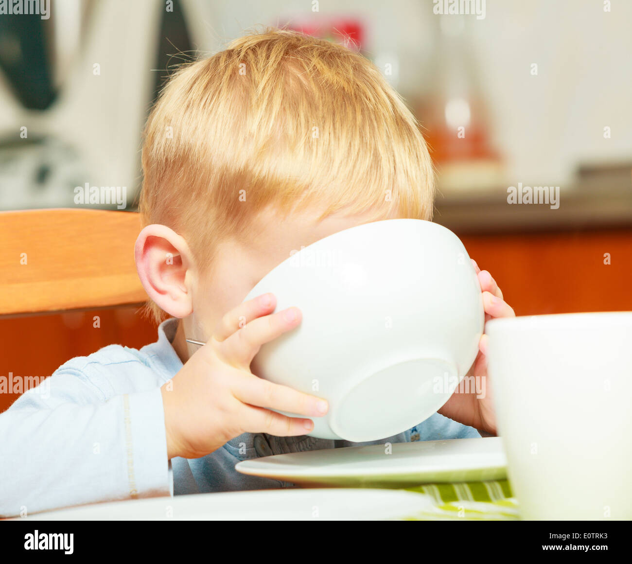 Happy childhood. Blond boy kid child eating corn flakes cereal with ...