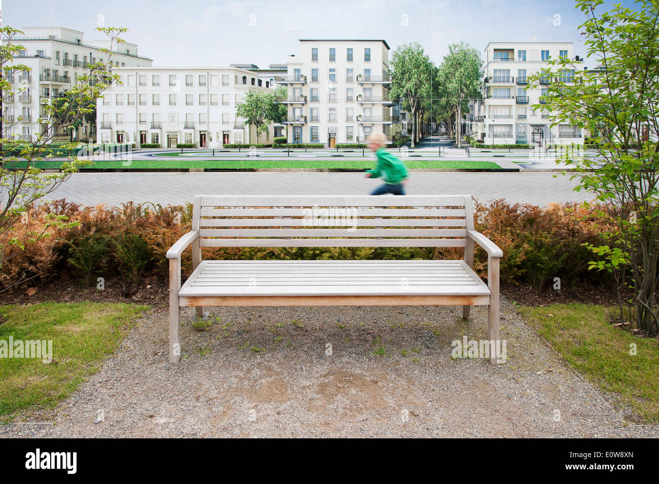Boy runs behind behind park bench outdoors in front of a two ...