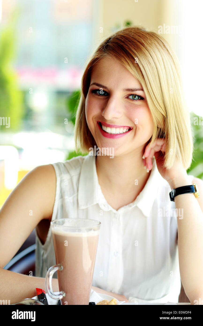 Young smiling woman sitting in cafe Stock Photo - Alamy