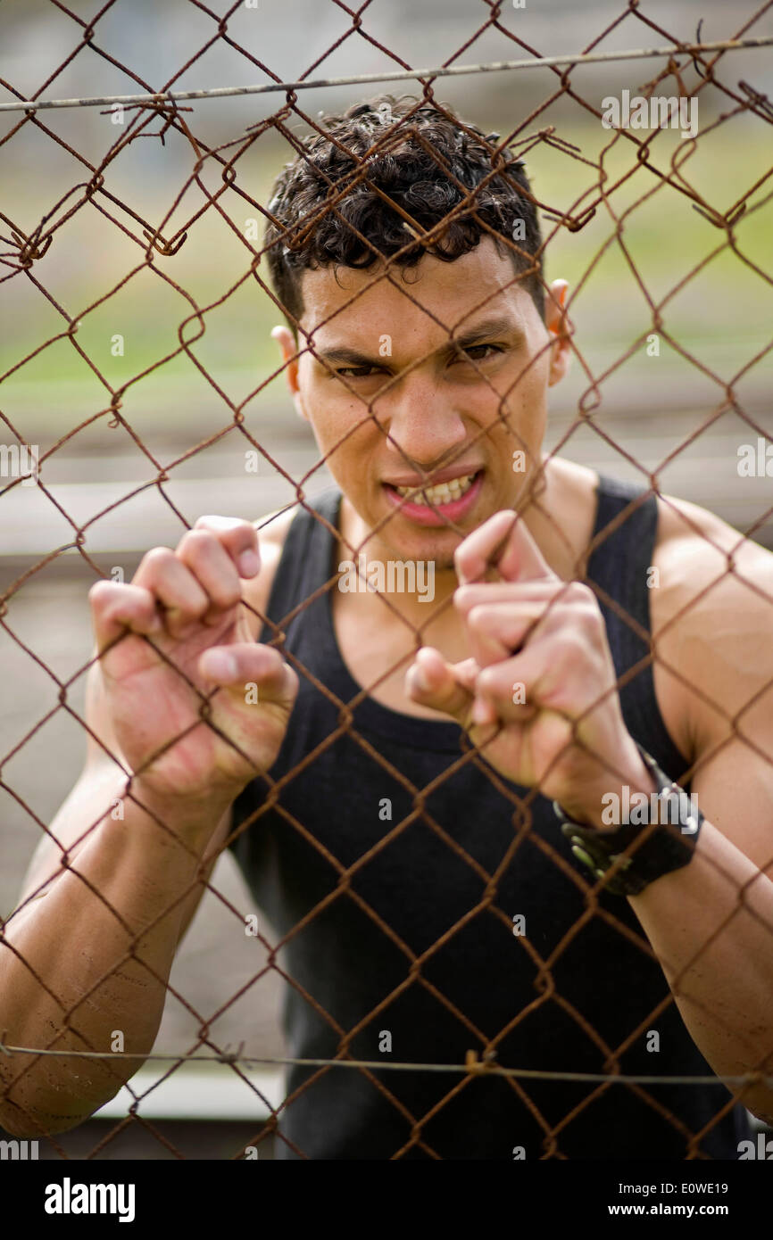 Young man holding onto a fence Stock Photo - Alamy