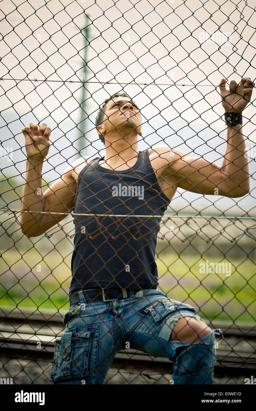 Young man climbing a fence Stock Photo - Alamy