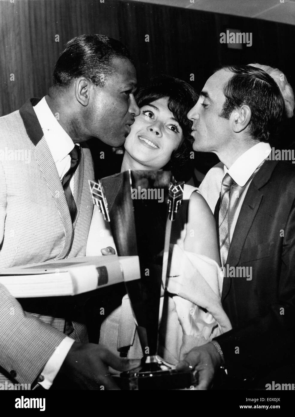 Sugar Ray Robinson and Charles Aznavour giving Dany Carrel a kiss Stock ...