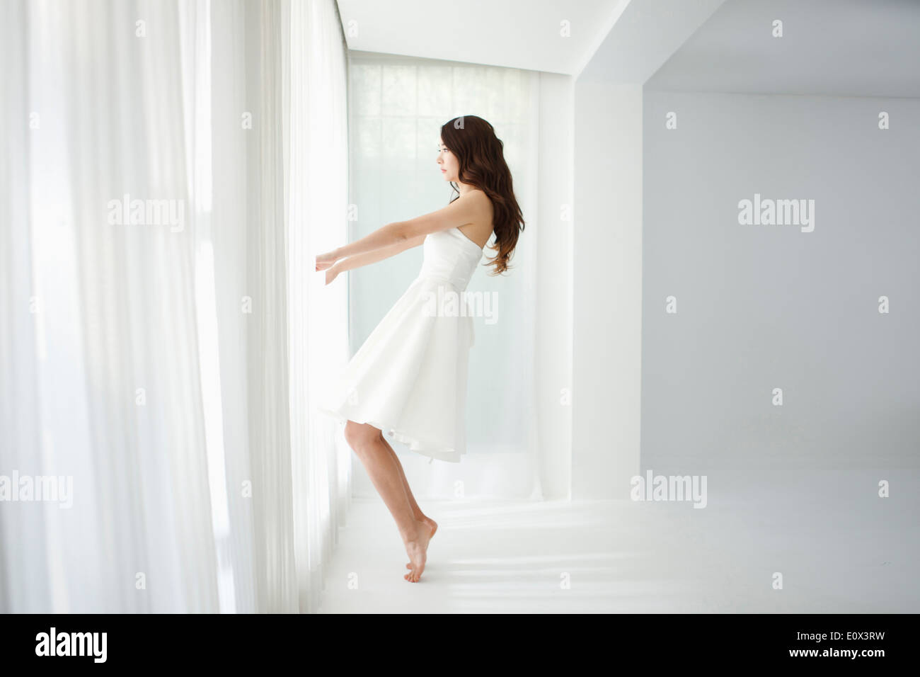 a woman opening a window of a white room Stock Photo - Alamy