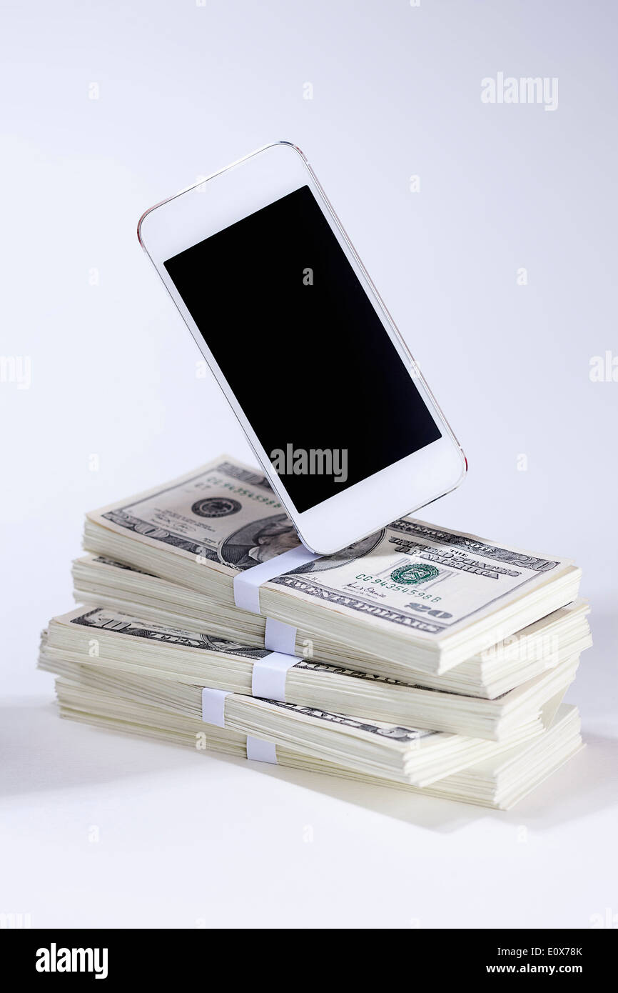 a smart phone on top of a pile of money Stock Photo - Alamy