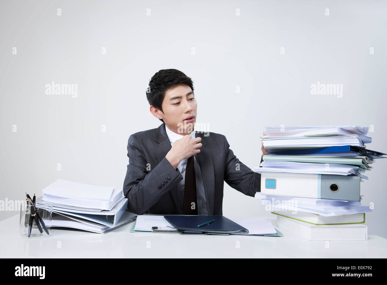 a business man sitting between two piles of work Stock Photo - Alamy