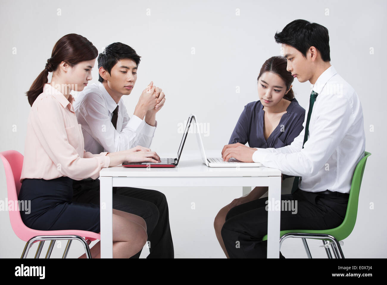 two business women and two business men working around a table Stock ...