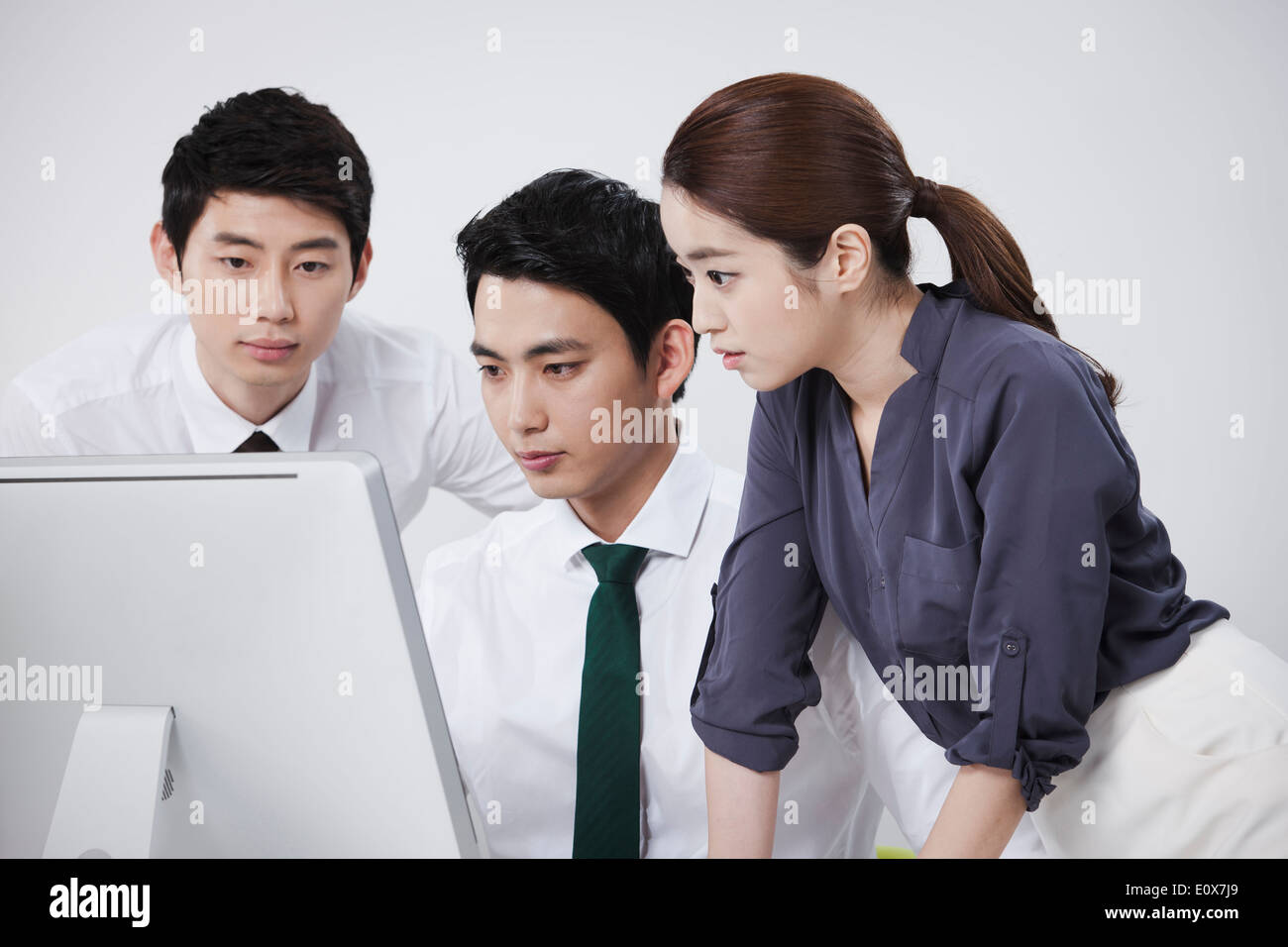 two business men and a business woman looking at a computer screen ...
