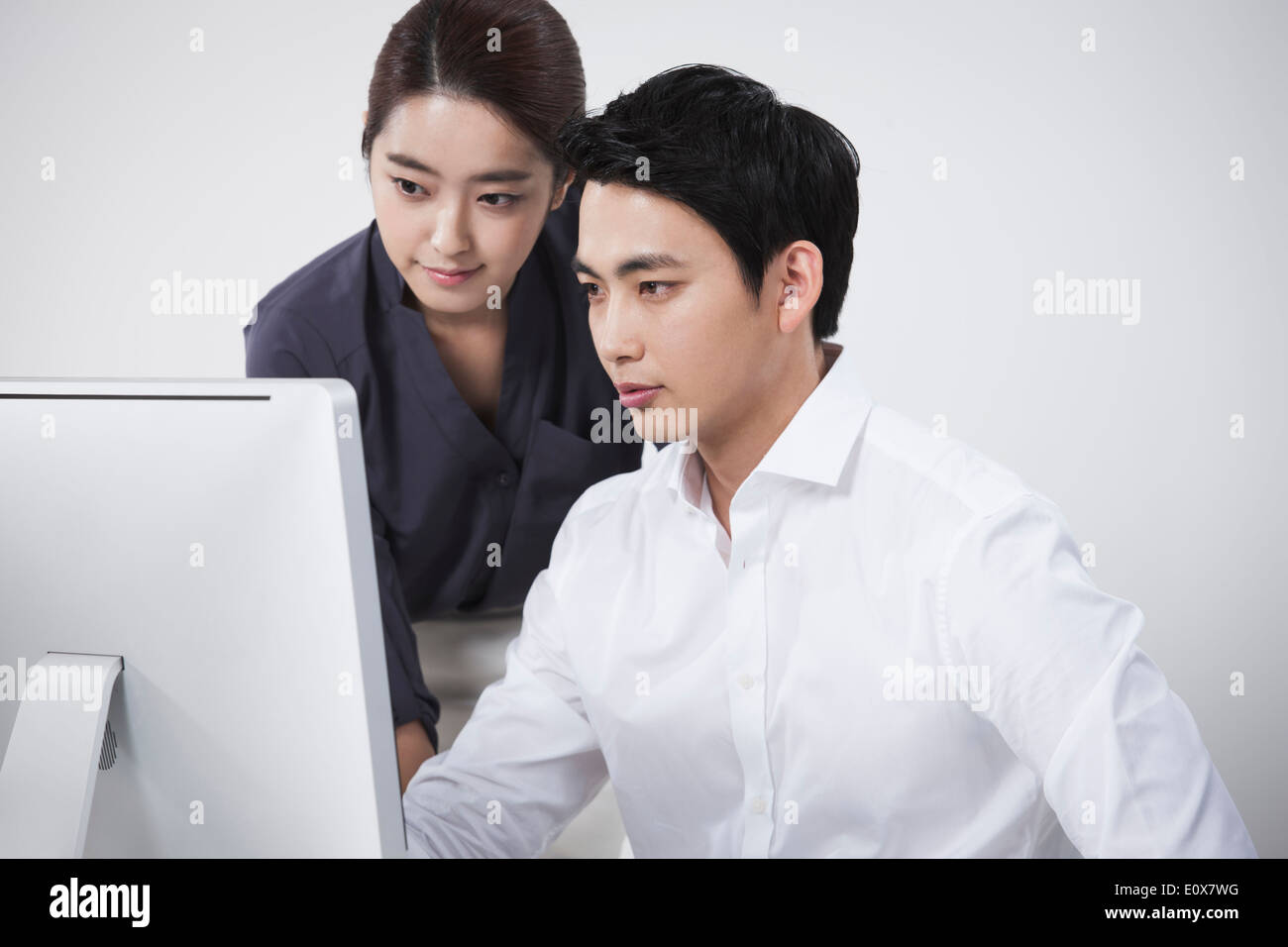 a business man and a business woman looking at a computer screen Stock ...
