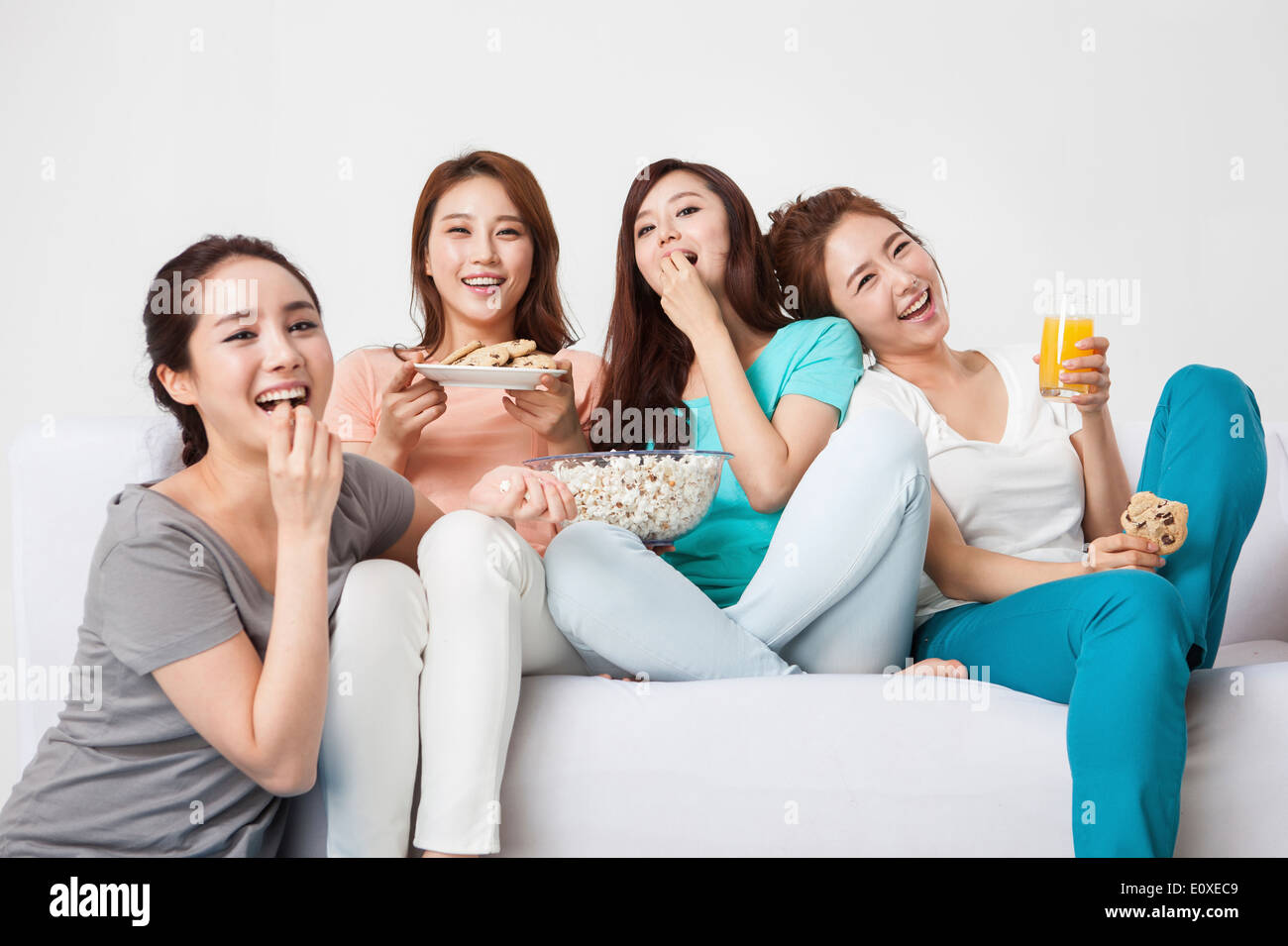 women sitting and eating on the couch Stock Photo - Alamy