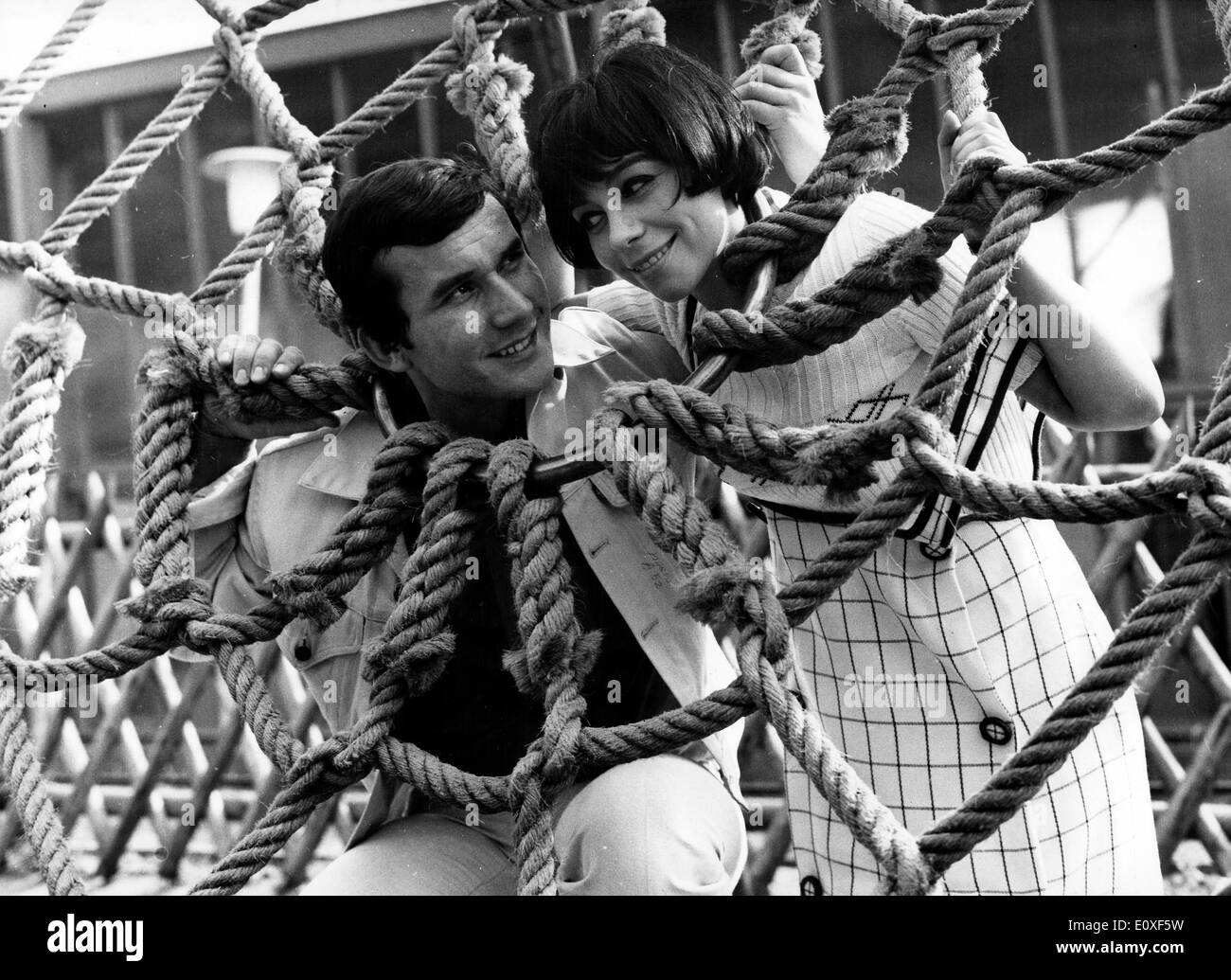 Actor Peter Beil and Ann Gogo with their head through a rope net Stock ...