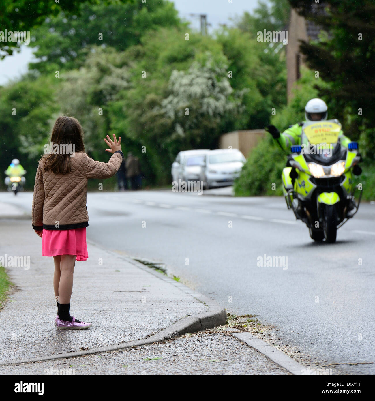 Young white girl waving at British police motorbike rider who waves ...