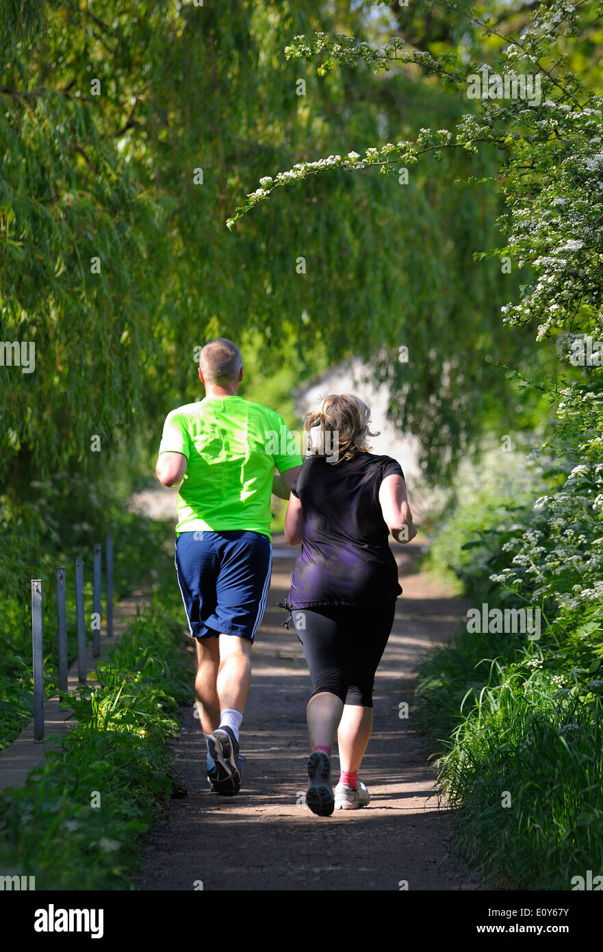 Caucasian couple running together on path uk Stock Photo - Alamy