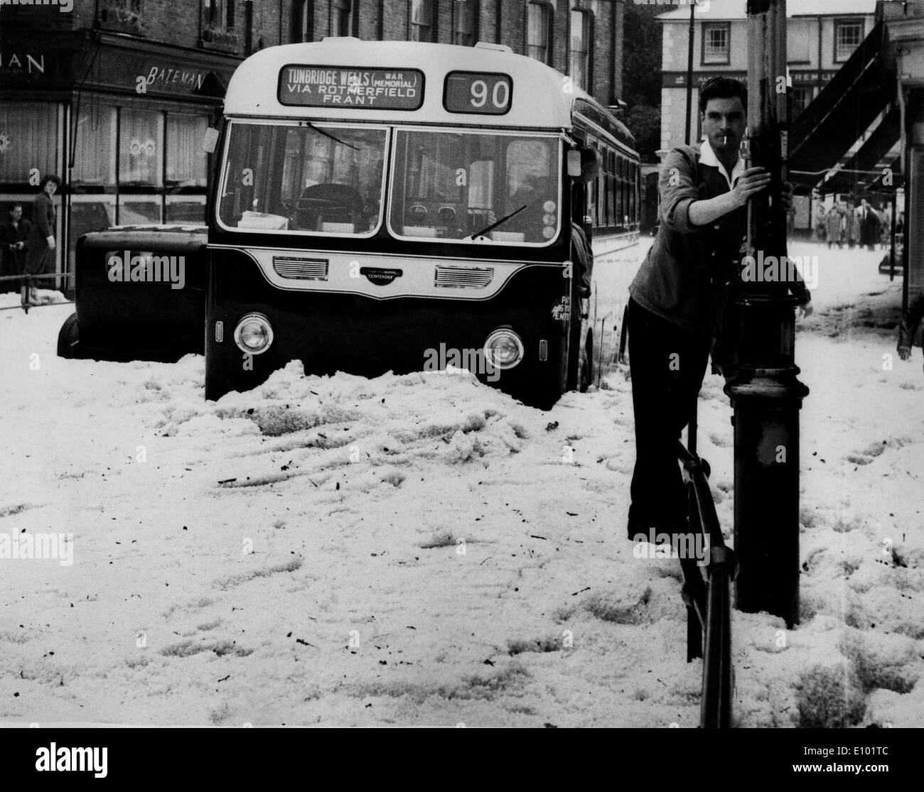 Bad Weather - a man smokes in front of a bus, standing on a metal fence ...