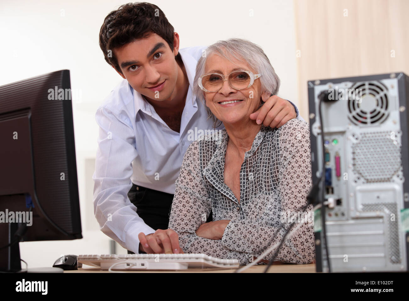 Young man helping an elderly lady use a computer Stock Photo - Alamy