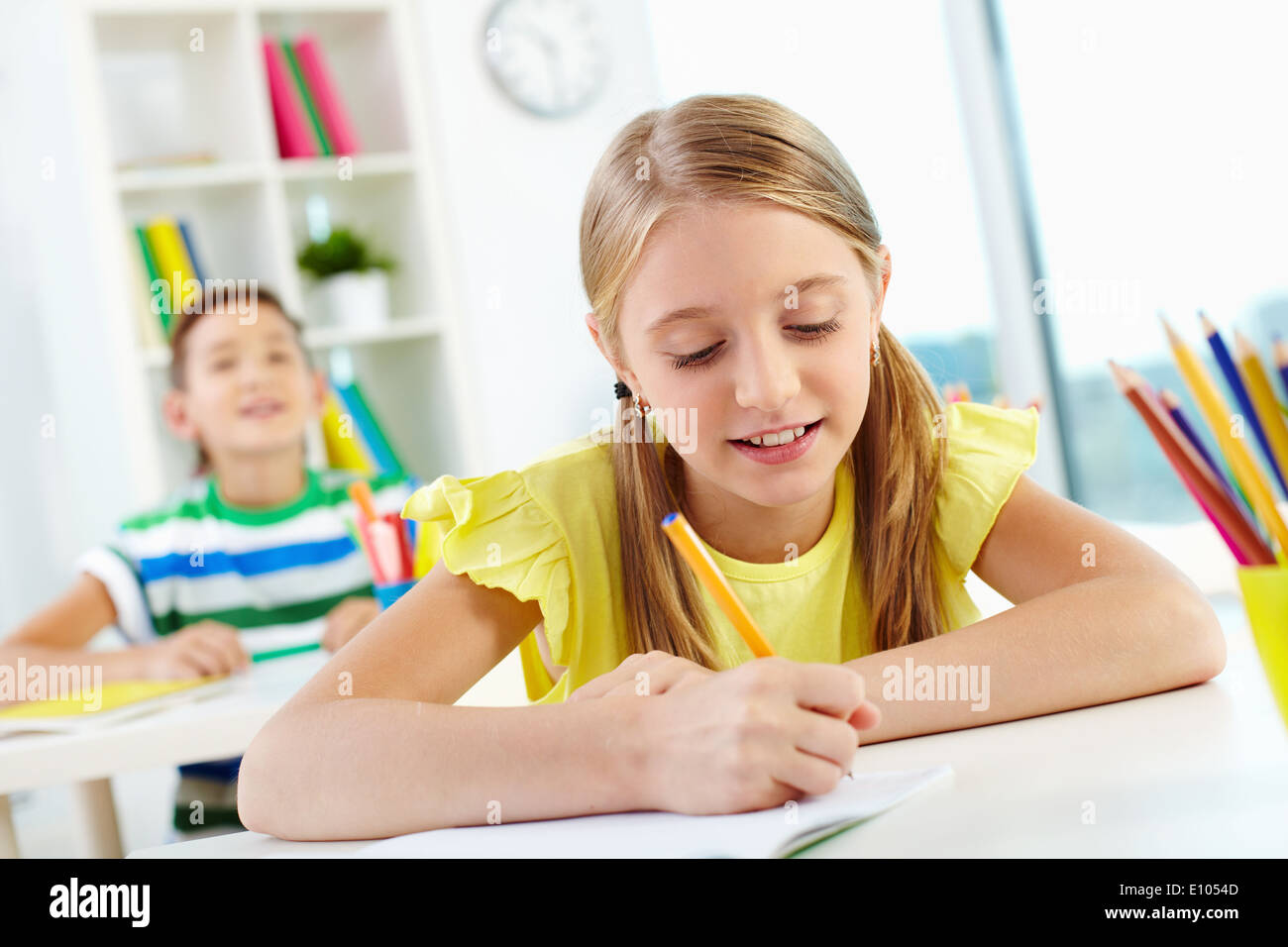 Lovely girl drawing at lesson on background of her classmate Stock ...