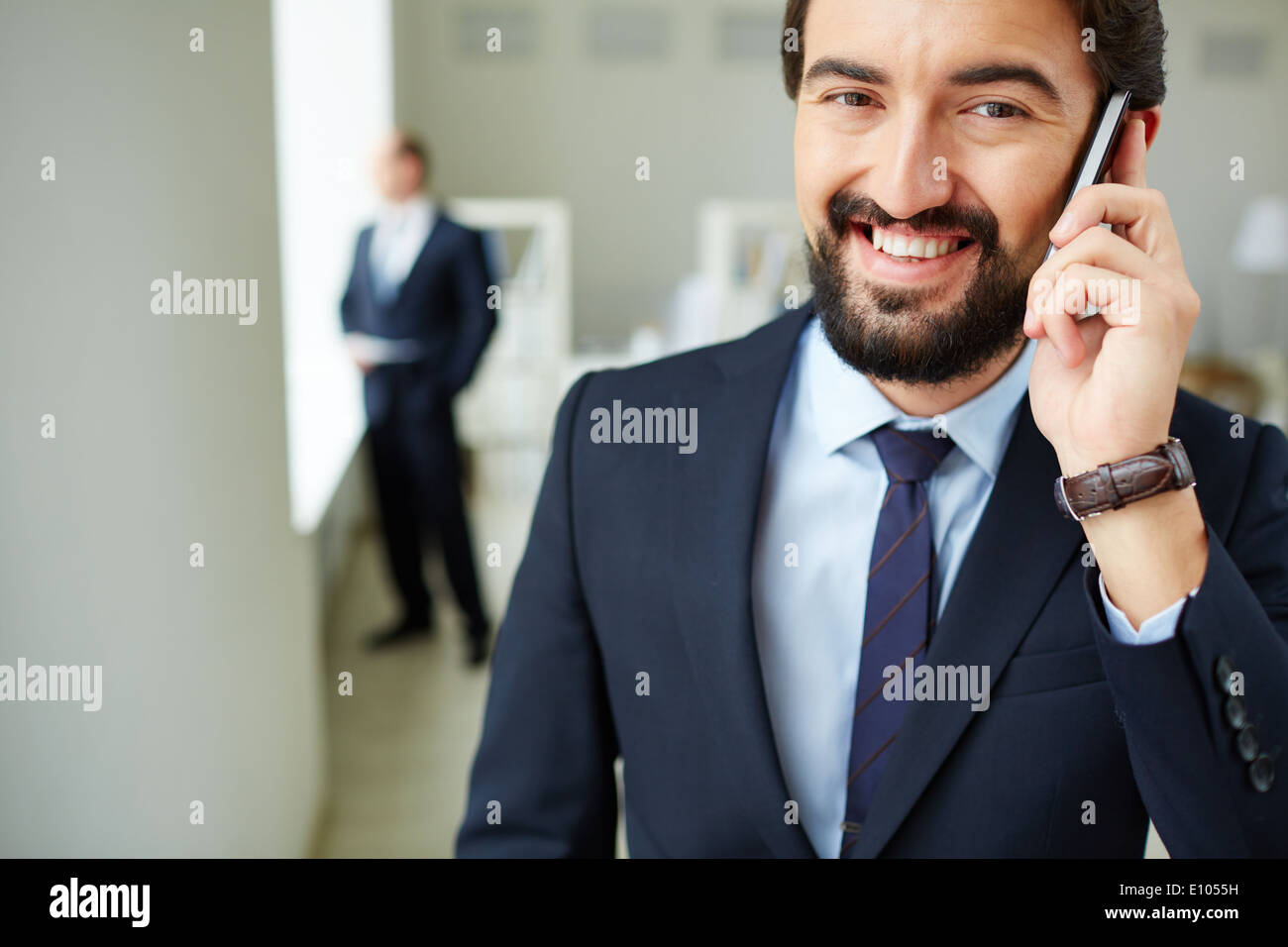Image of young businessman speaking on the phone and looking at camera ...