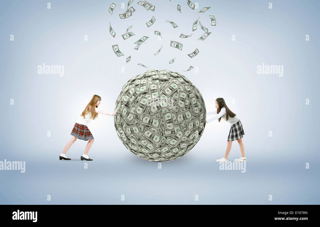two girls pushing a ball of money Stock Photo - Alamy