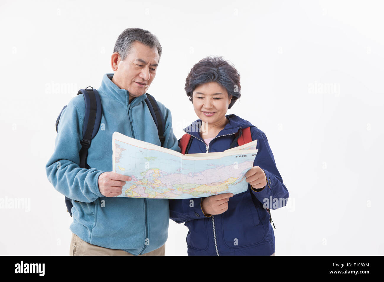 an old man and an old woman looking at a map Stock Photo - Alamy