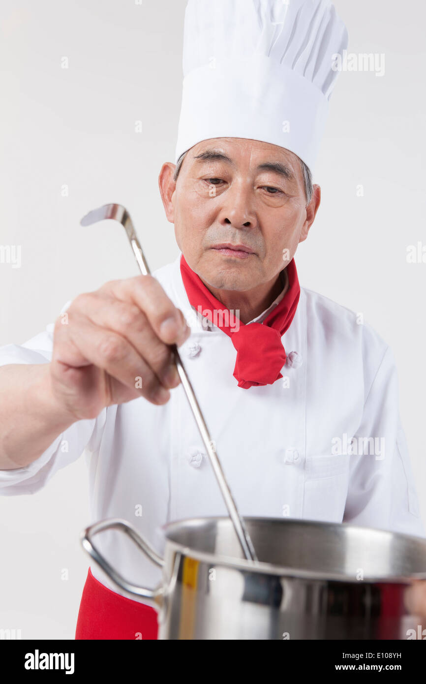 an old man in a chefs uniform cooking with a pot Stock Photo - Alamy