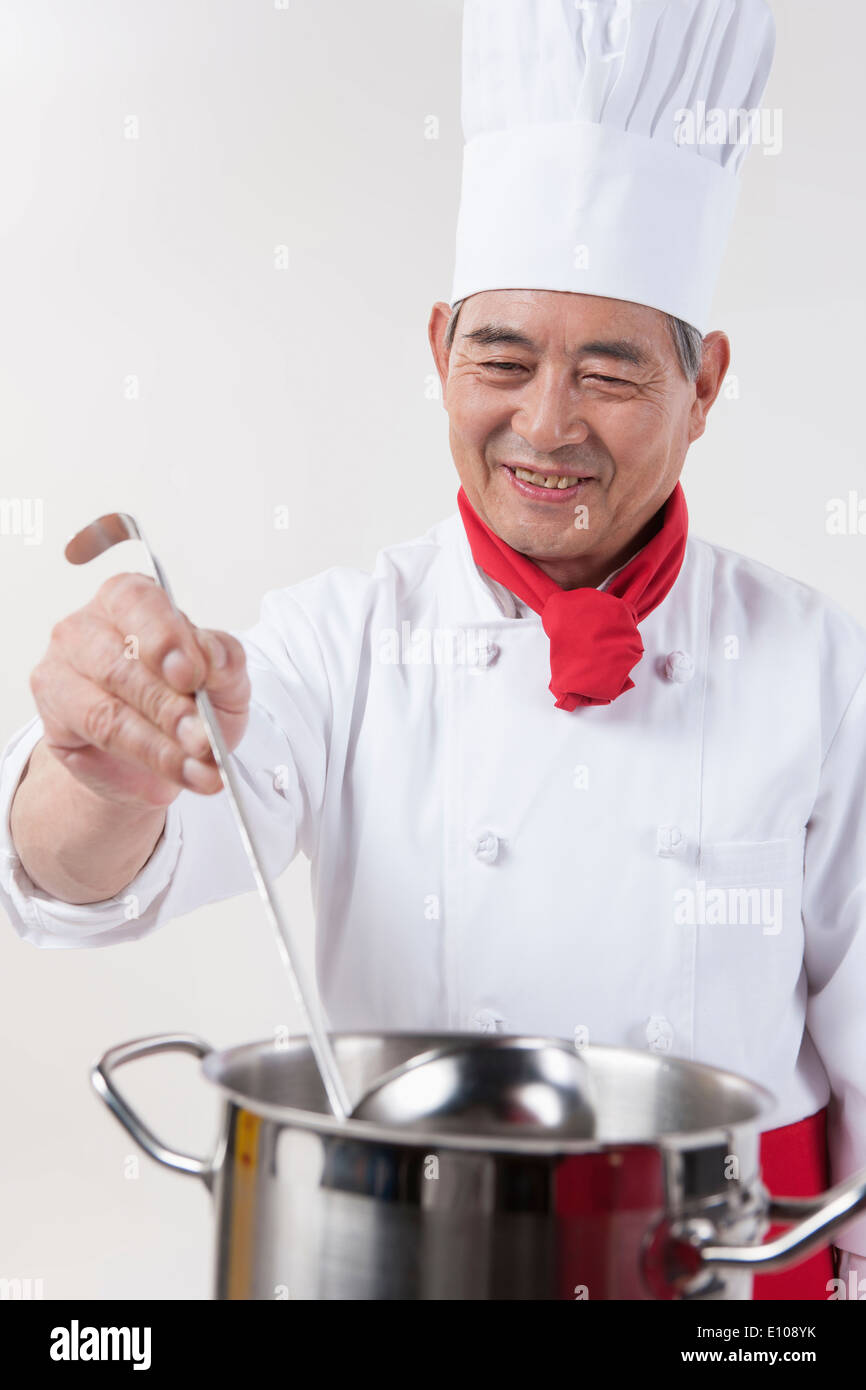 an old man in a chefs uniform cooking with a pot Stock Photo - Alamy