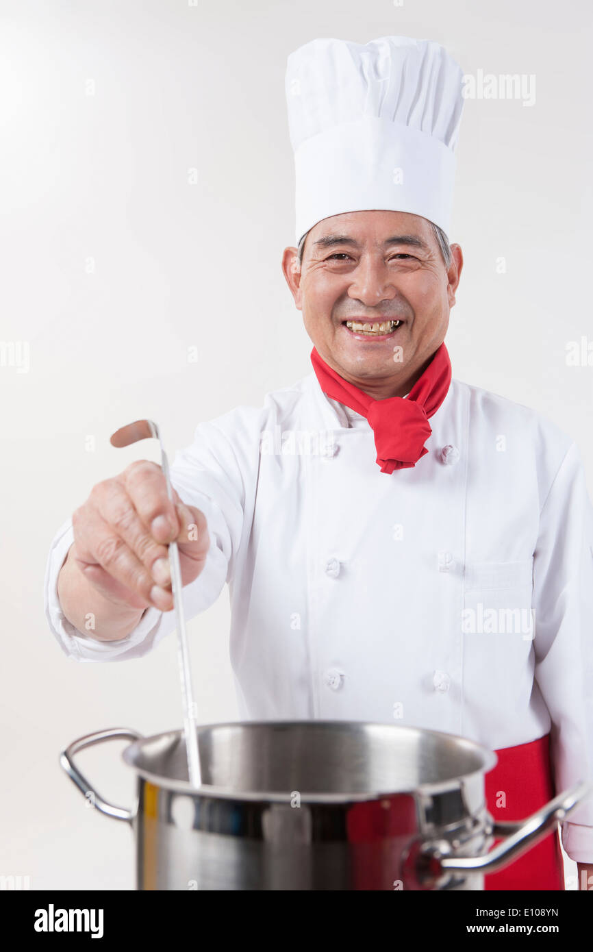 an old man in a chefs uniform cooking with a pot Stock Photo - Alamy
