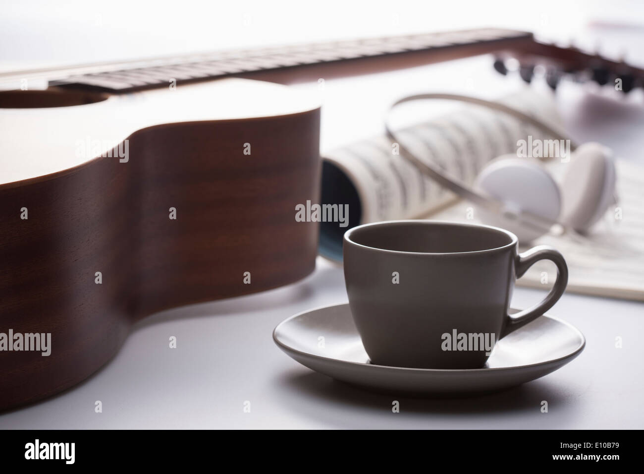 a coffee cup next to an acoustic guitar Stock Photo - Alamy