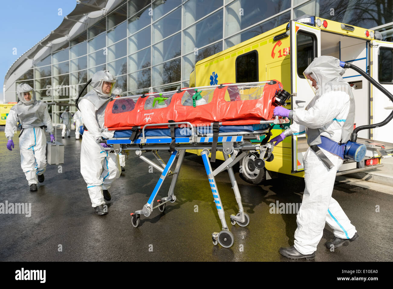 HAZMAT medical team pushing stretcher by ambulance on street Stock ...