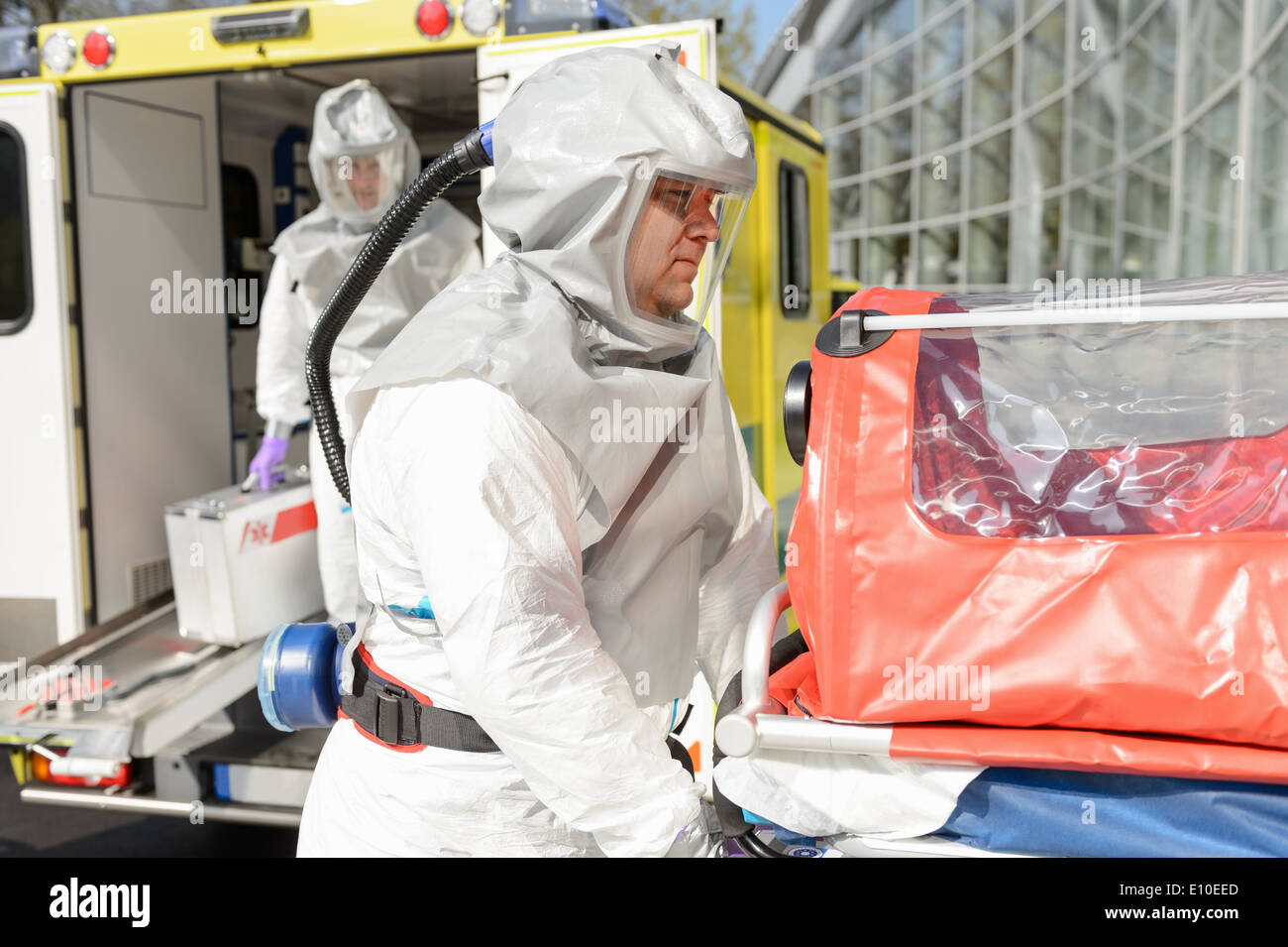Biohazard medical team member with stretcher outdoors by ambulance ...