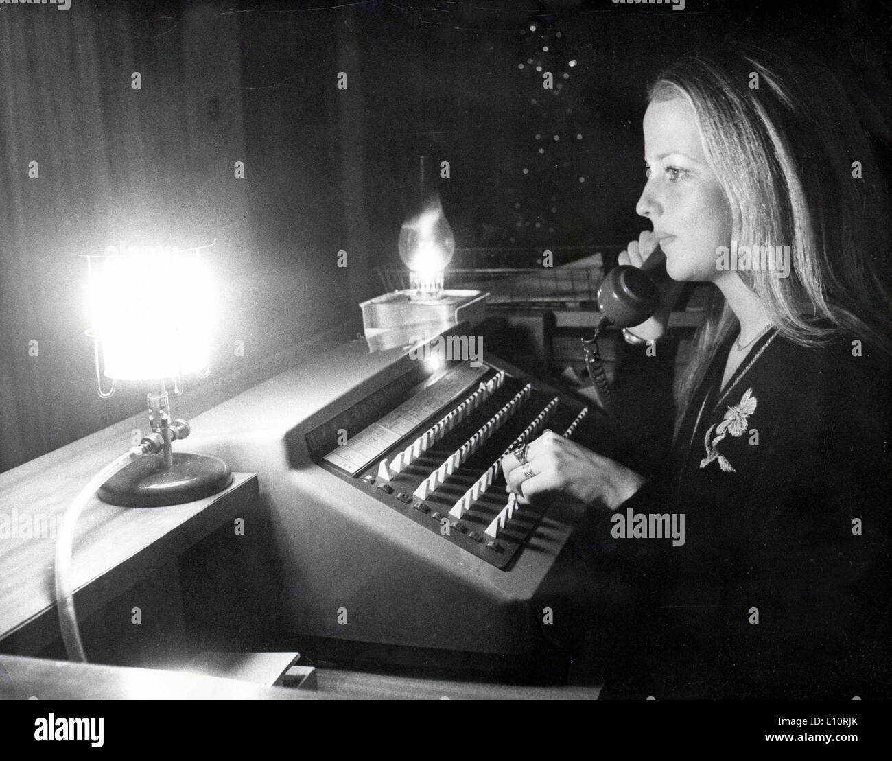 Telephone operator working by emergency lighting in a telephone center ...
