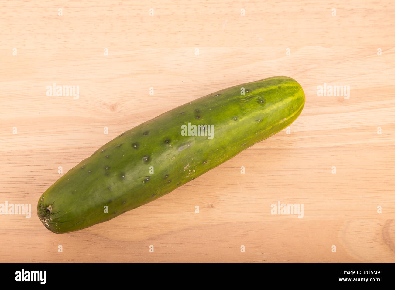 A whole green cucumber on a wood table Stock Photo - Alamy