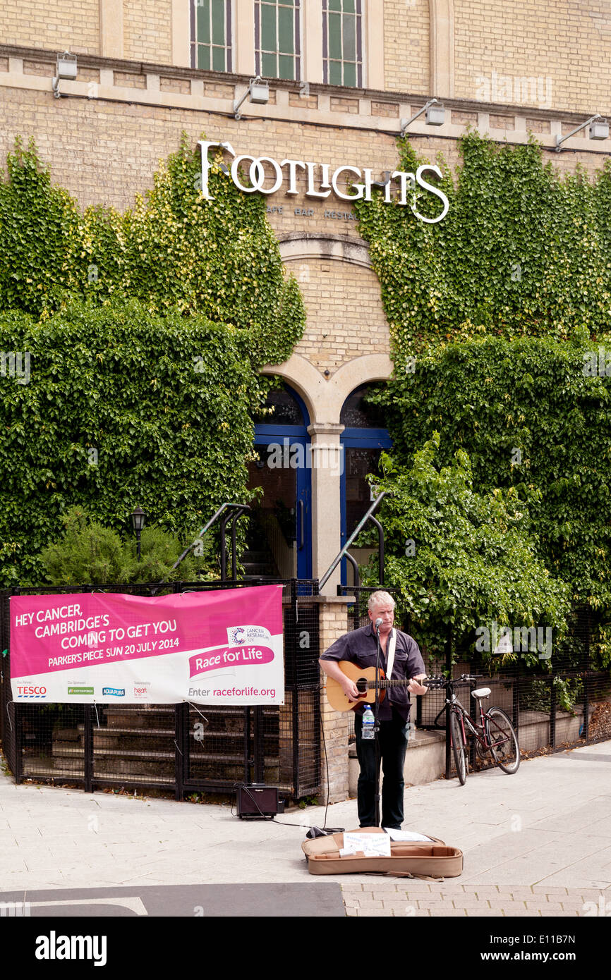 Street entertainer playing a guitar outside Footlights restaurant ...