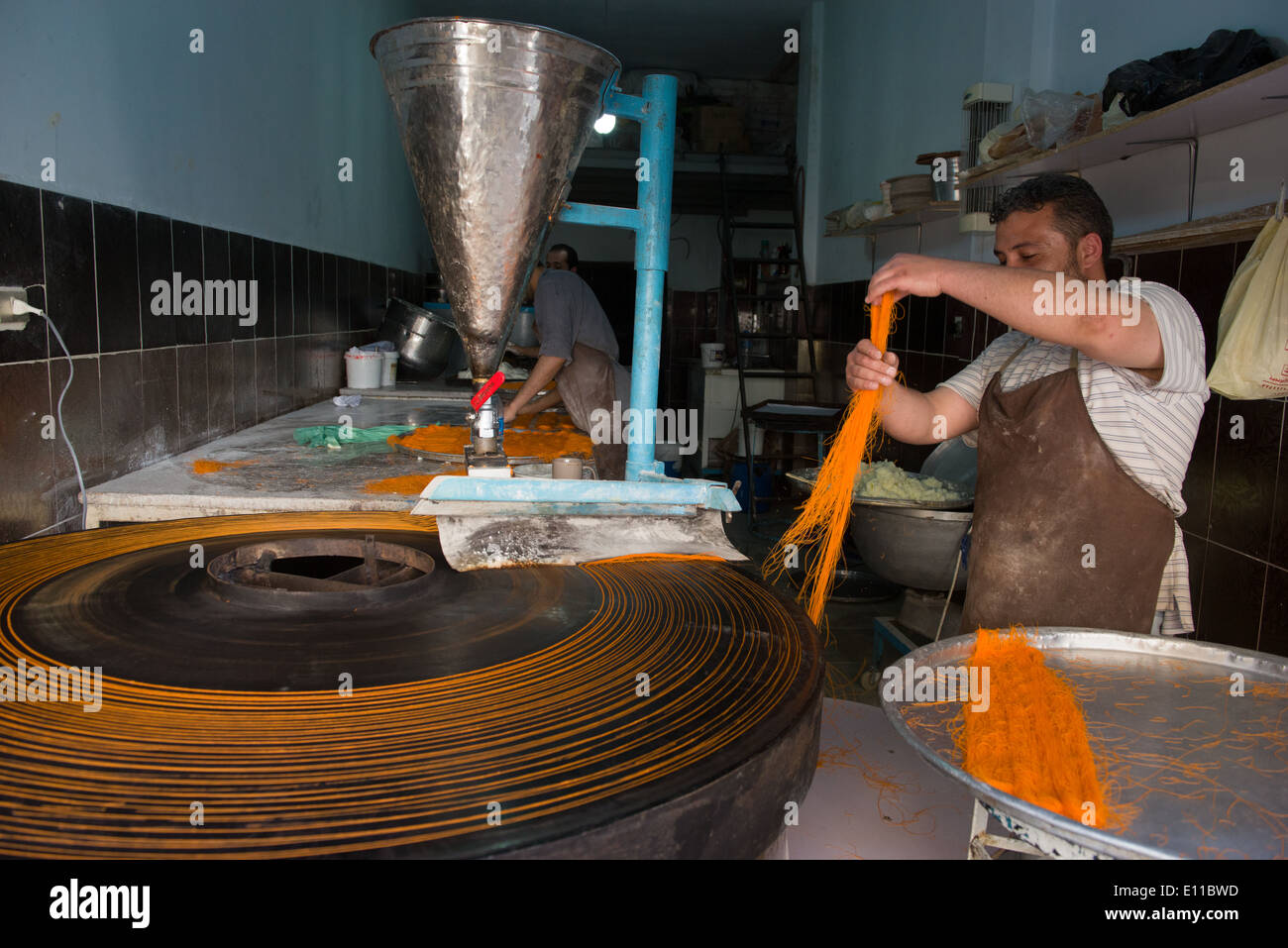 Man making sugar sweet strings in a small roadside kitchen, Madaba ...