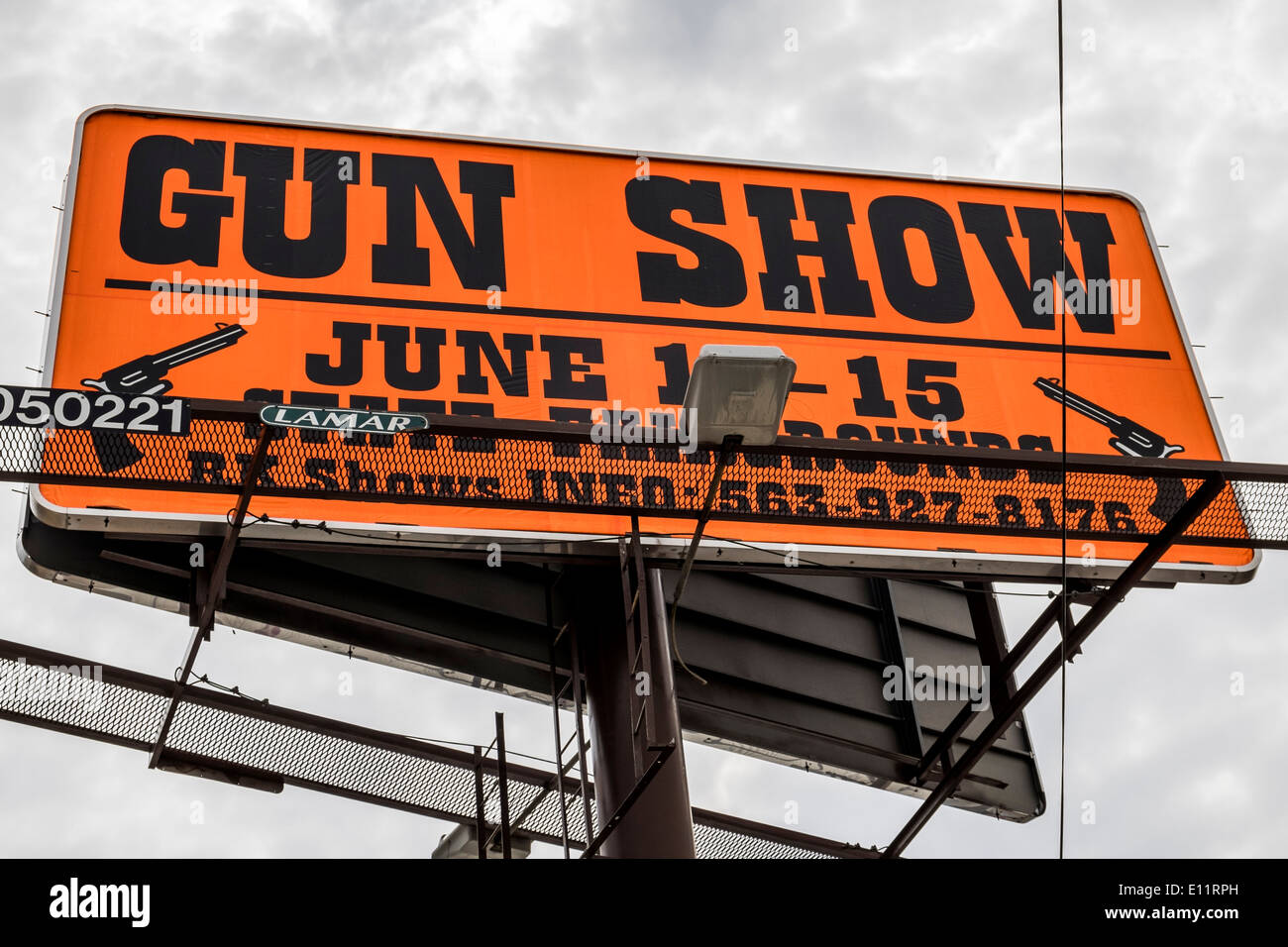An orange sign painted with black letters advertising a gun show in ...