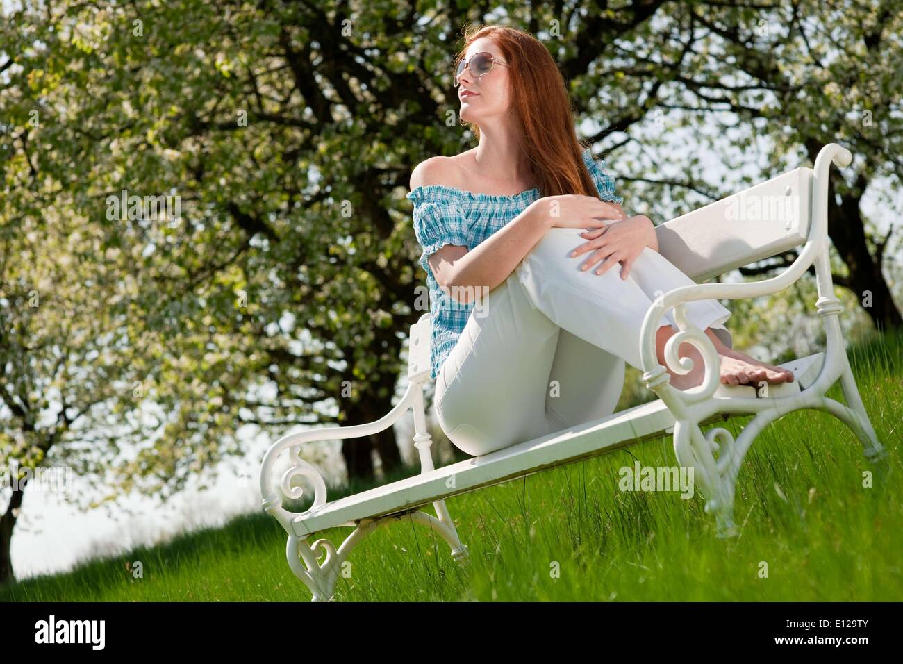 Woman sitting barefoot on a bench in the park hi-res stock photography ...