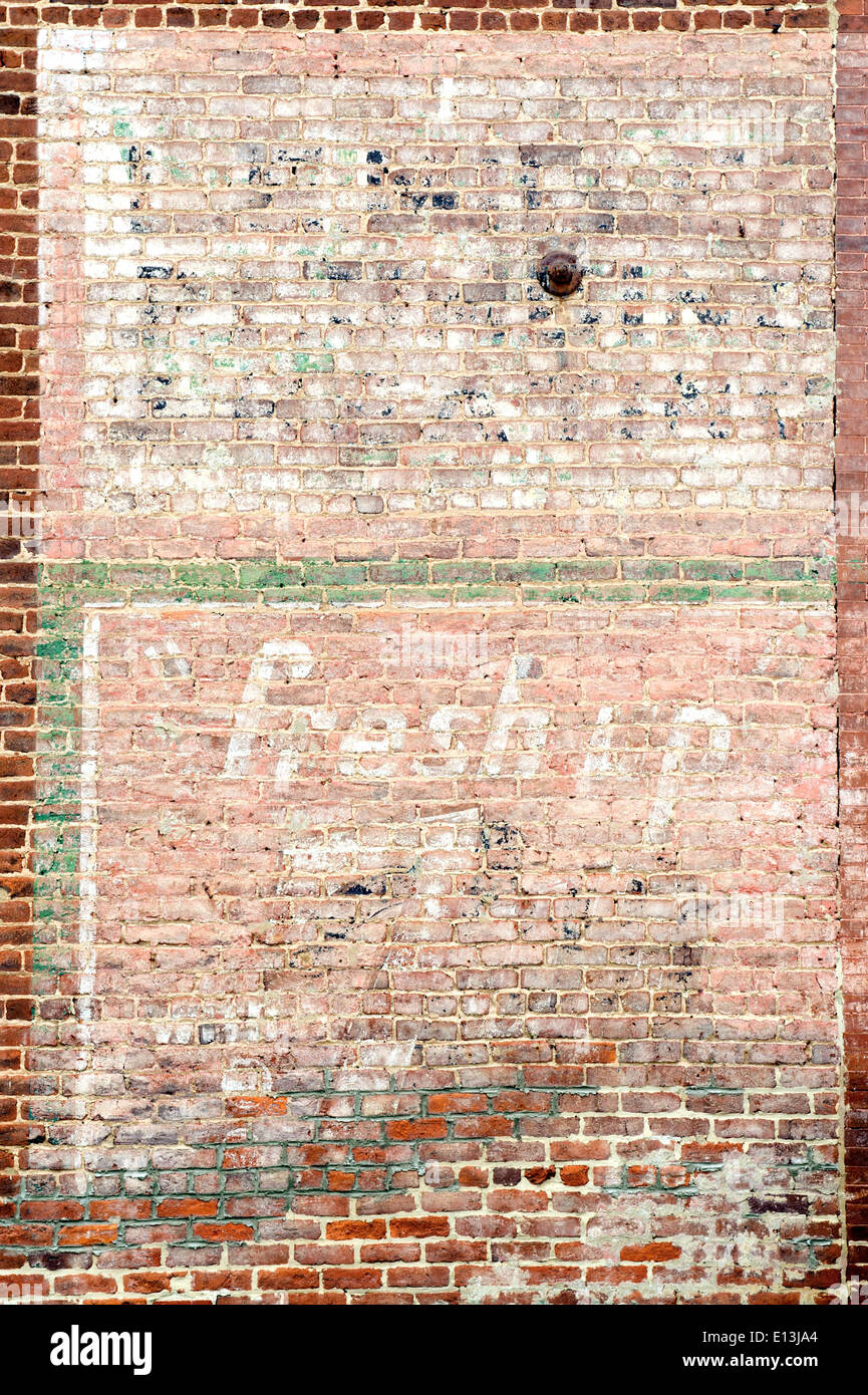 Old faded advertisement painted on the side of a brick building in ...