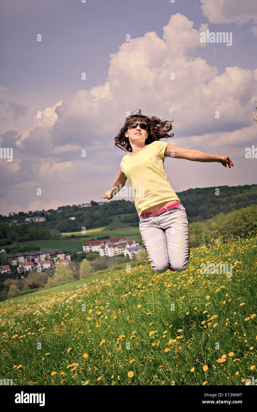a young jumping woman in front of rural landscape Stock Photo - Alamy
